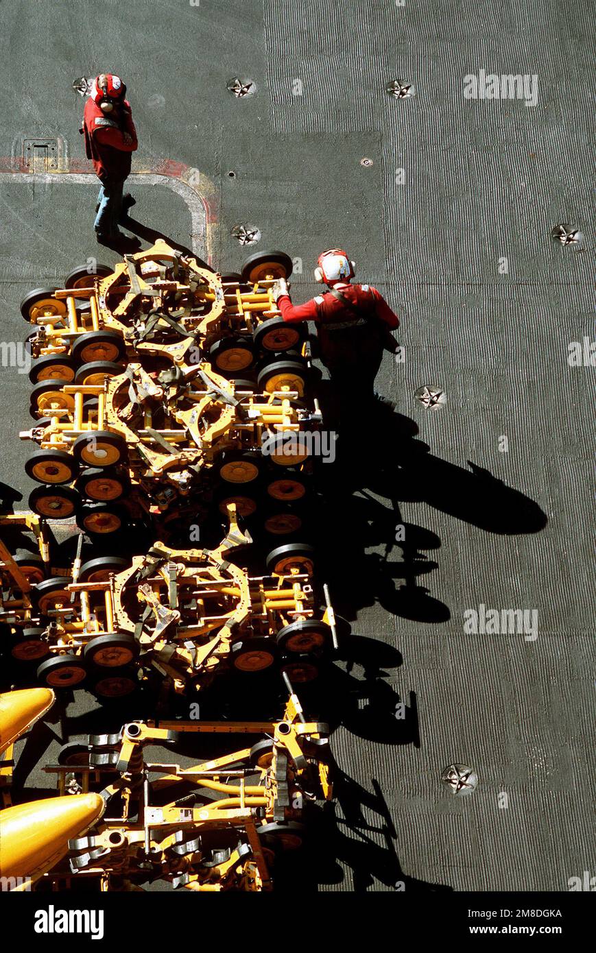 Aviation ordnancemen wait beside stacks of folded-up weapons skids on ...