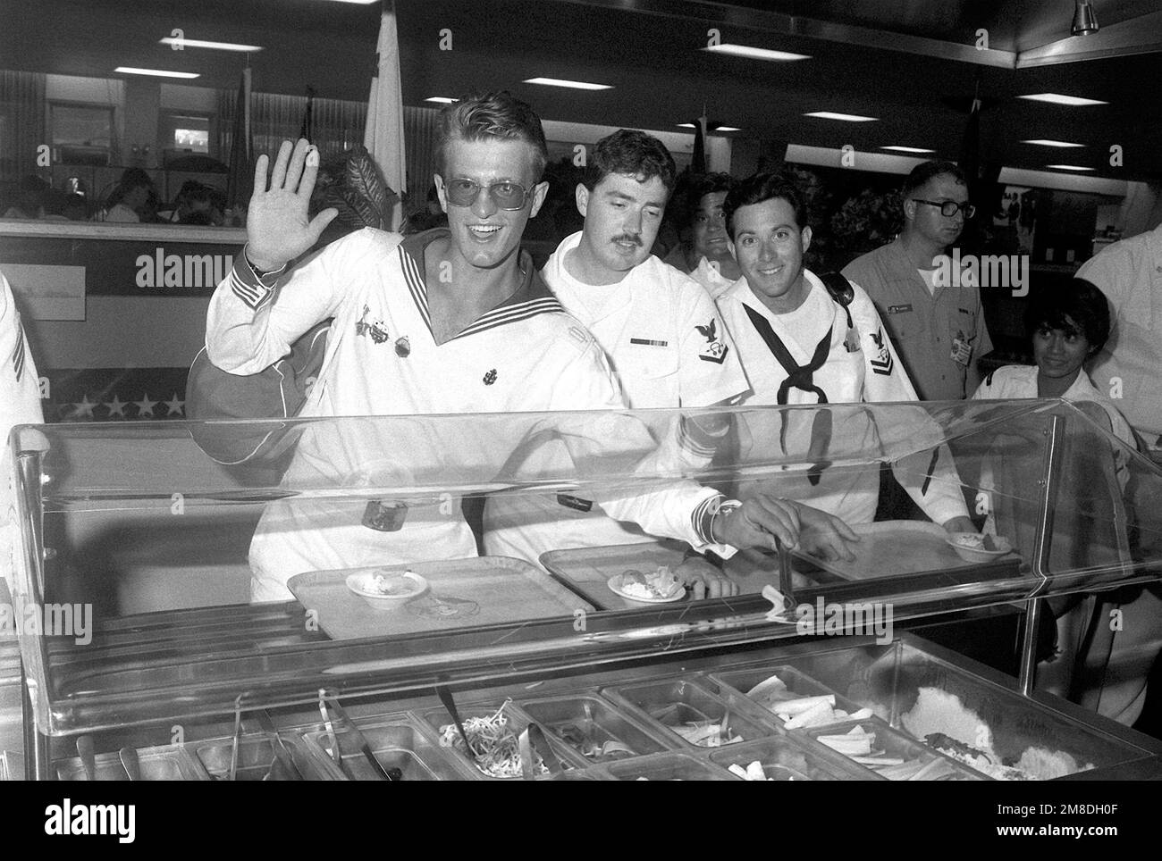 A Soviet sailor waves as he makes his way through the mess line at the ...
