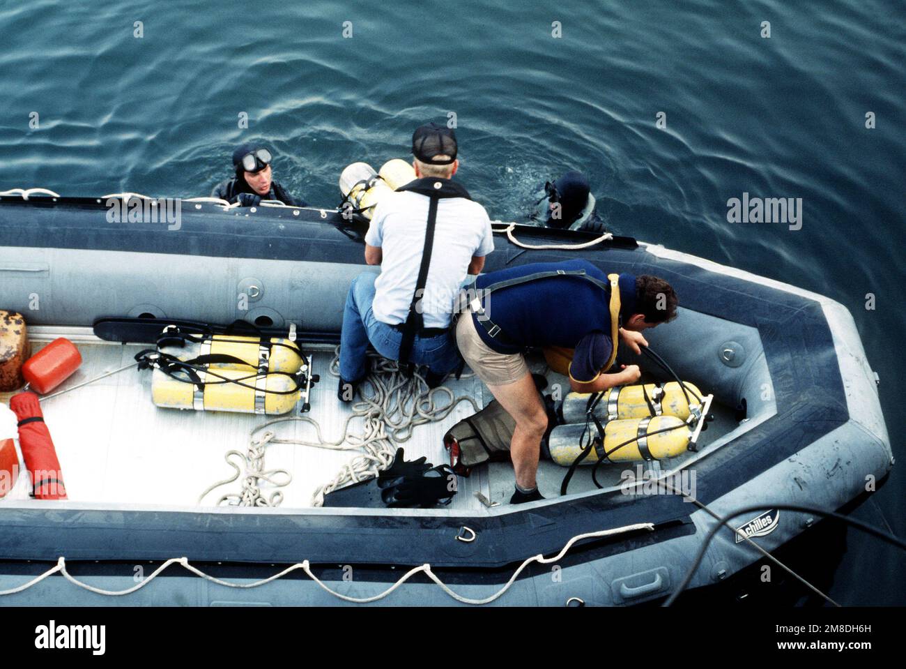 Navy divers pass their gear over the side of an inflatable boat after ...