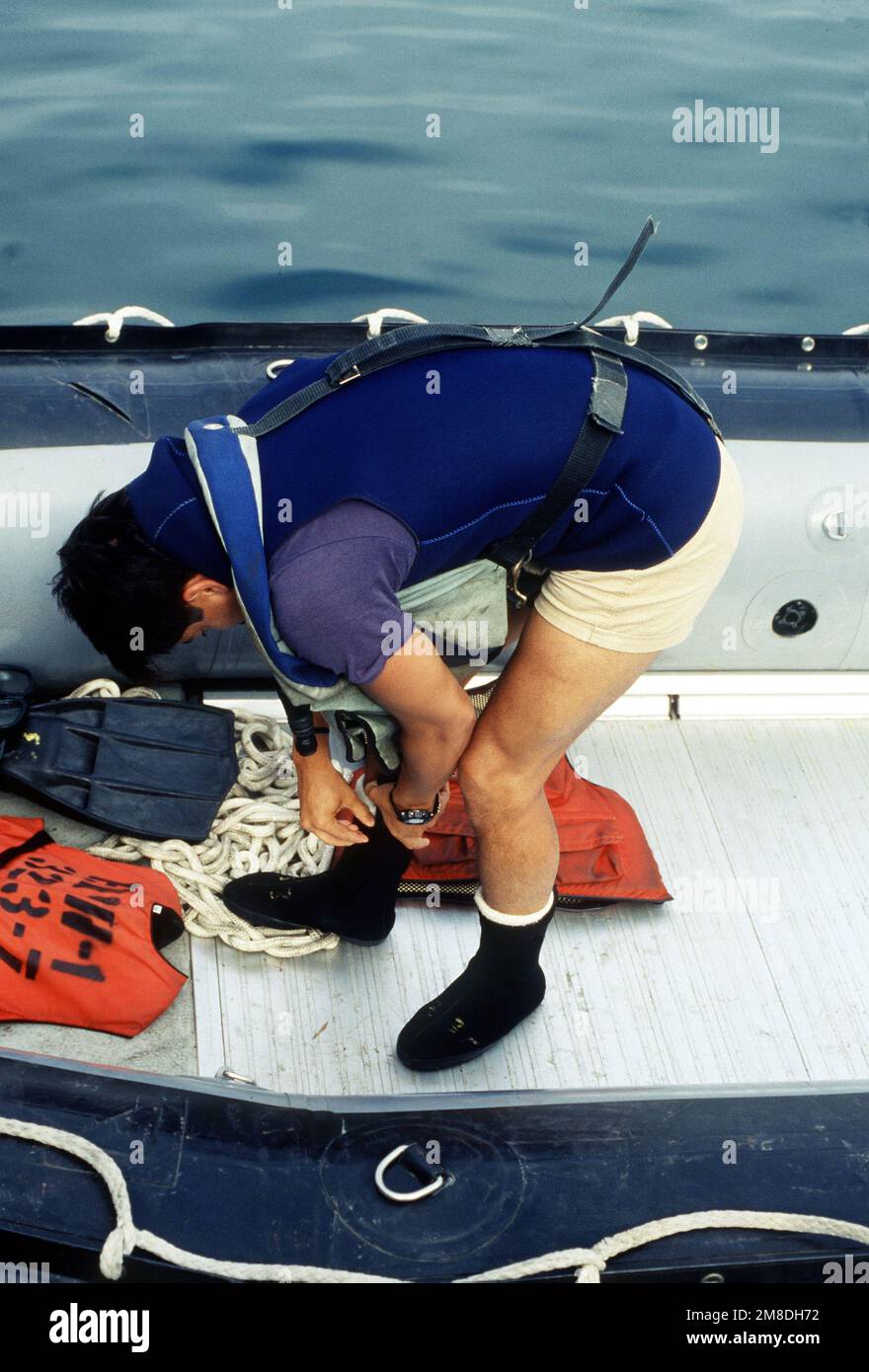 A Navy diver removes his gear in an inflatable boat after performing ...