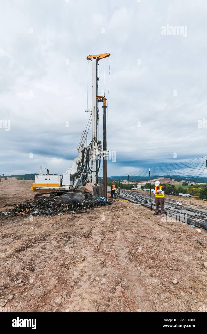 Workers and a methane gas well drilling rig at an active landfill Stock ...