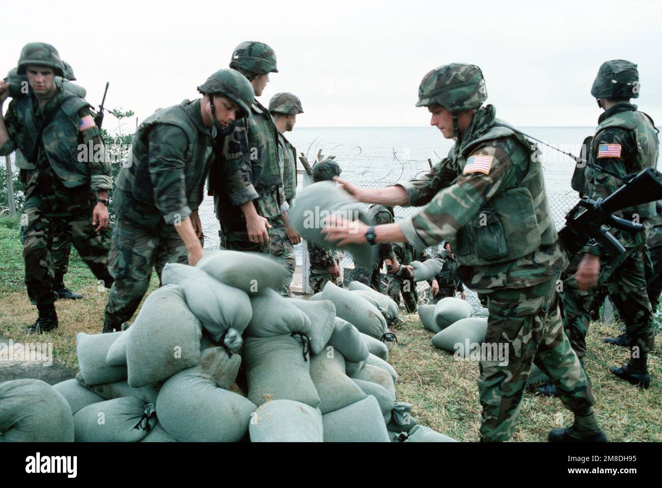 Marines pile up sandbags that are being filled on the beach at the edge ...