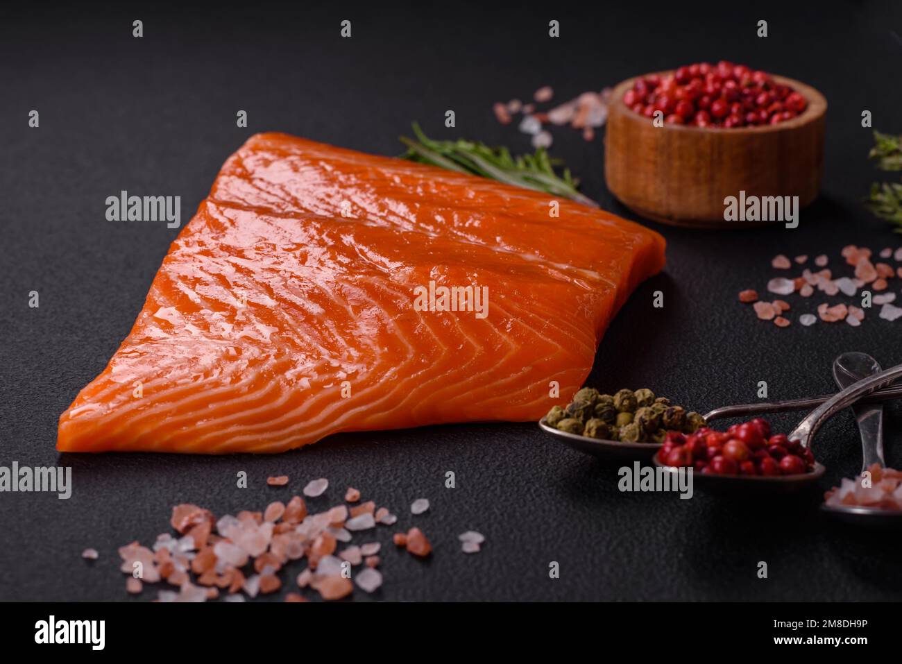Fillet of raw red salmon fish with salt, spices and herbs on a dark ...