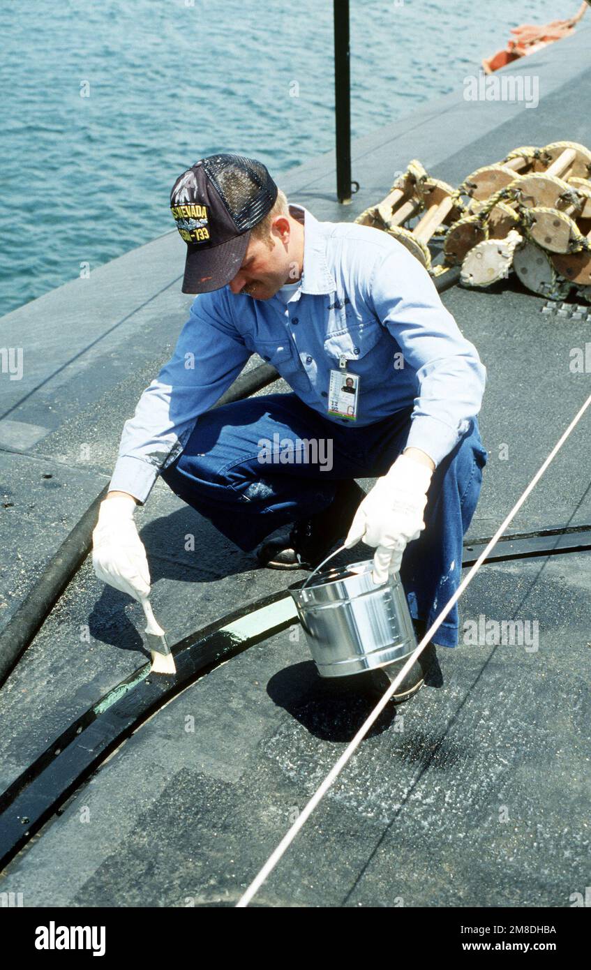 A crewman paints the safety track on the deck of the nuclear-powered ...