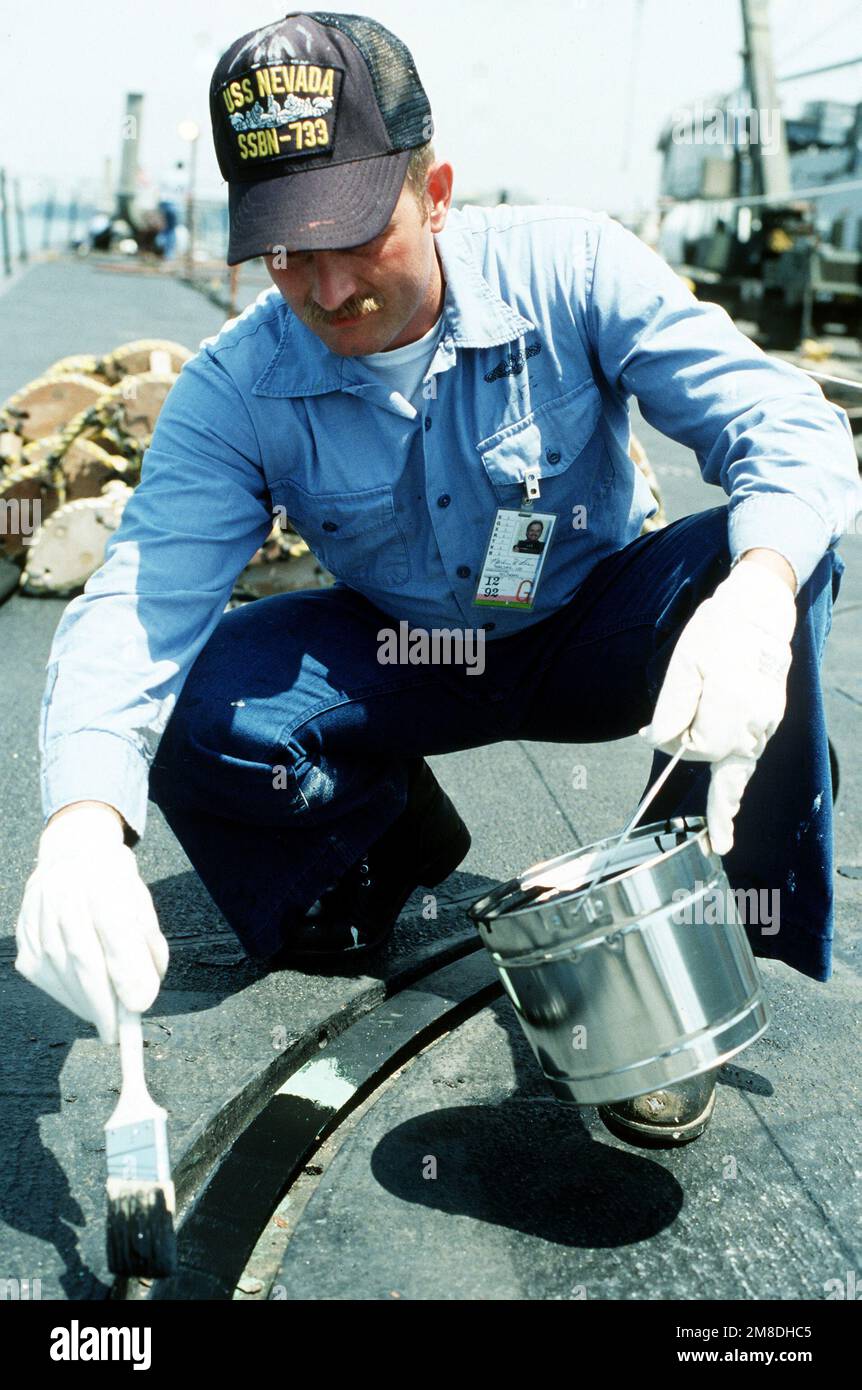 A crewman paints the safety track on the deck of the nuclear-powered ...