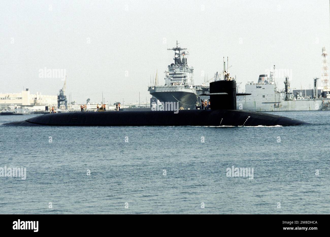 Line handlers stand by on deck as the nuclear-powered strategic missile ...