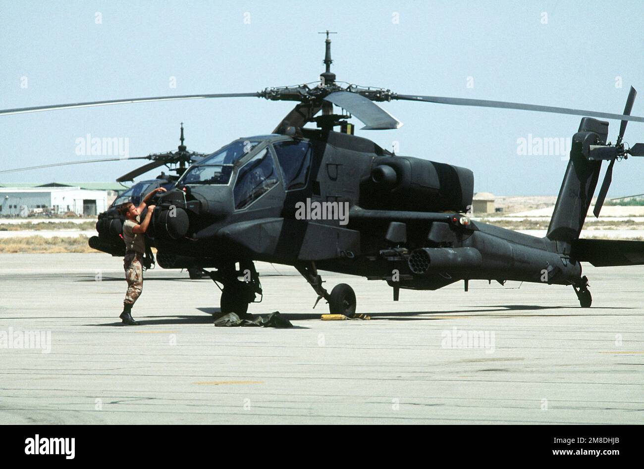 A soldier performs maintenance on an AH-64 Apache helicopter during ...