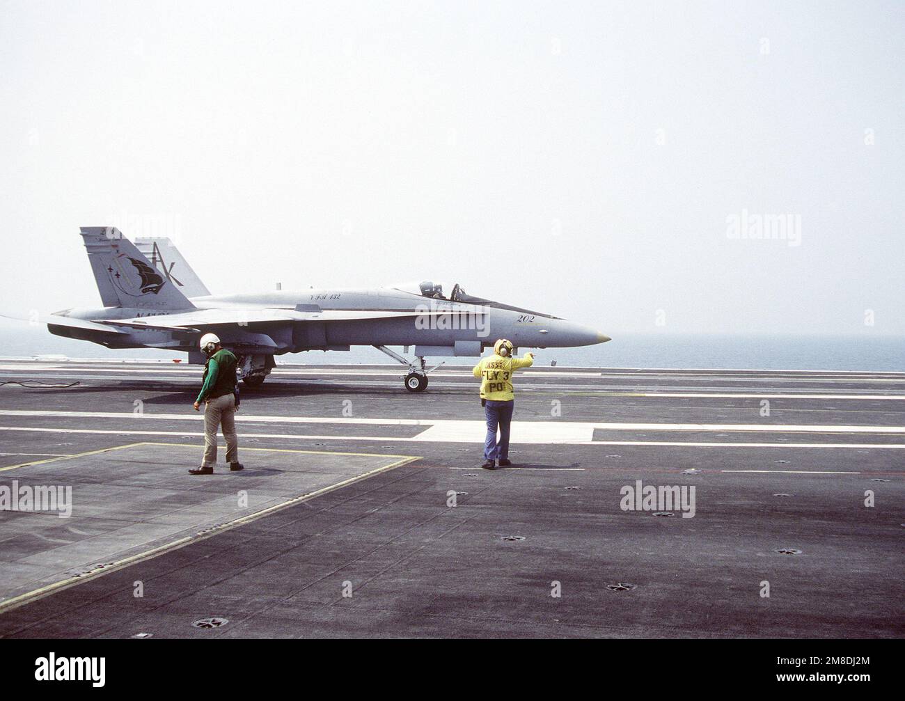 A plane director signals to the pilot of a Strike Fighter Squadron 132 ...