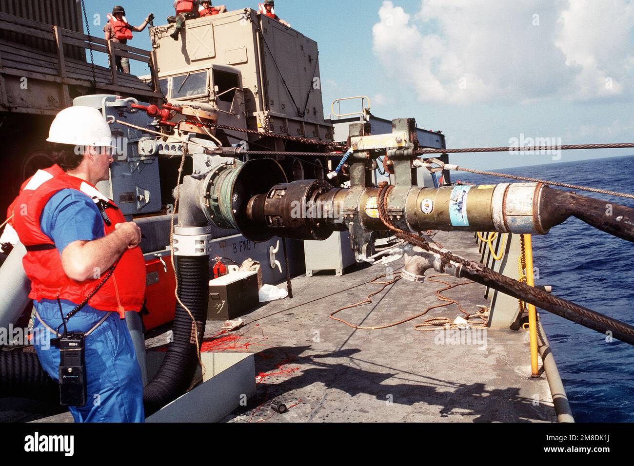 A civilian crew member stands by alongside the refueling hose aboard ...