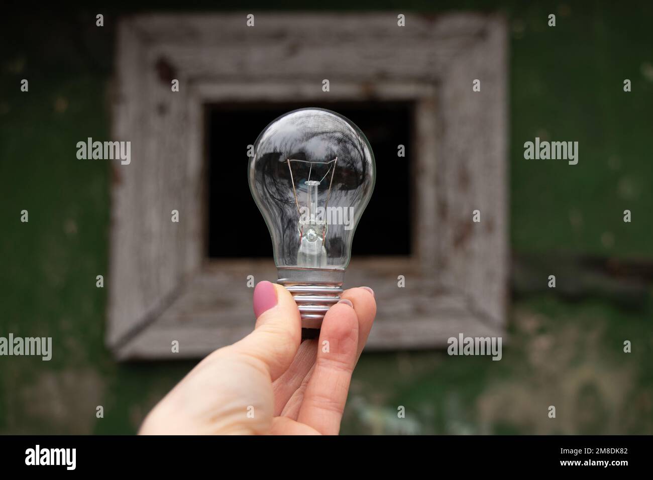 An incandescent light bulb in the hands of a girl against the ...