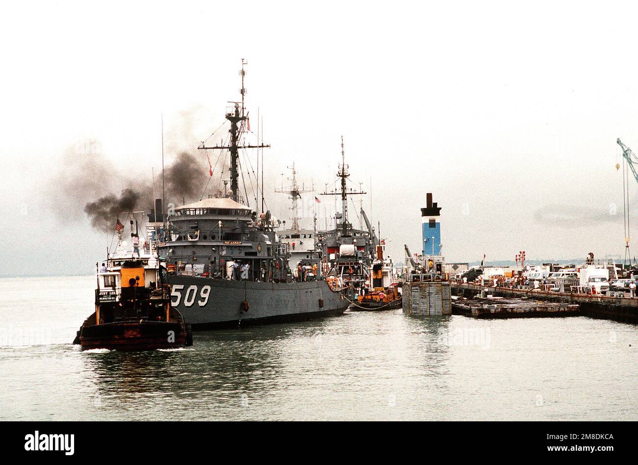 A tug boat pushes the ocean minesweeper USS ADROIT (MSO-509) over the ...