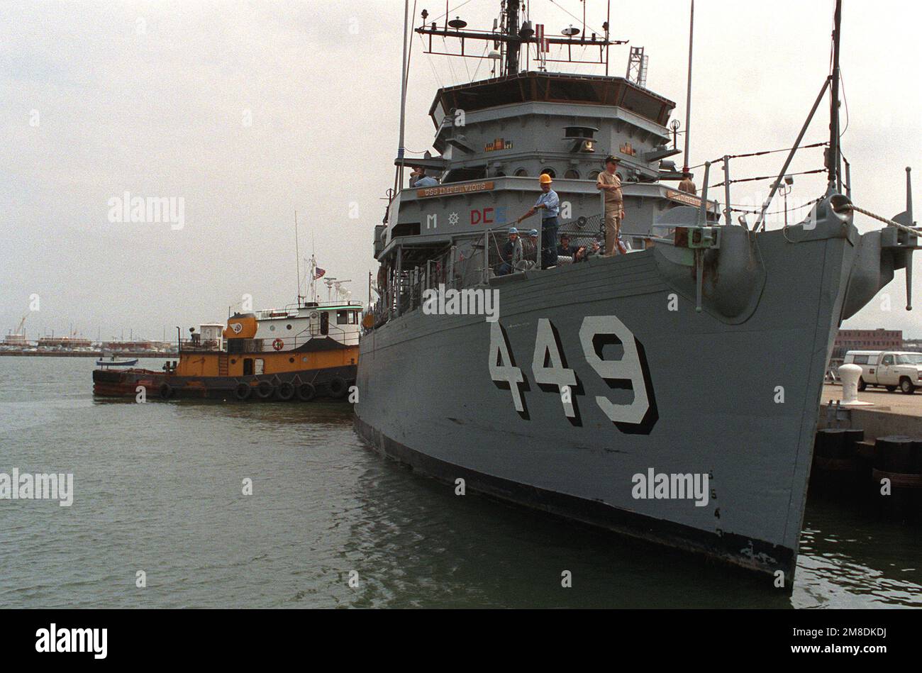 A tug boat moves in to guide the ocean minesweeper USS IMPERVIOUS (MSO ...