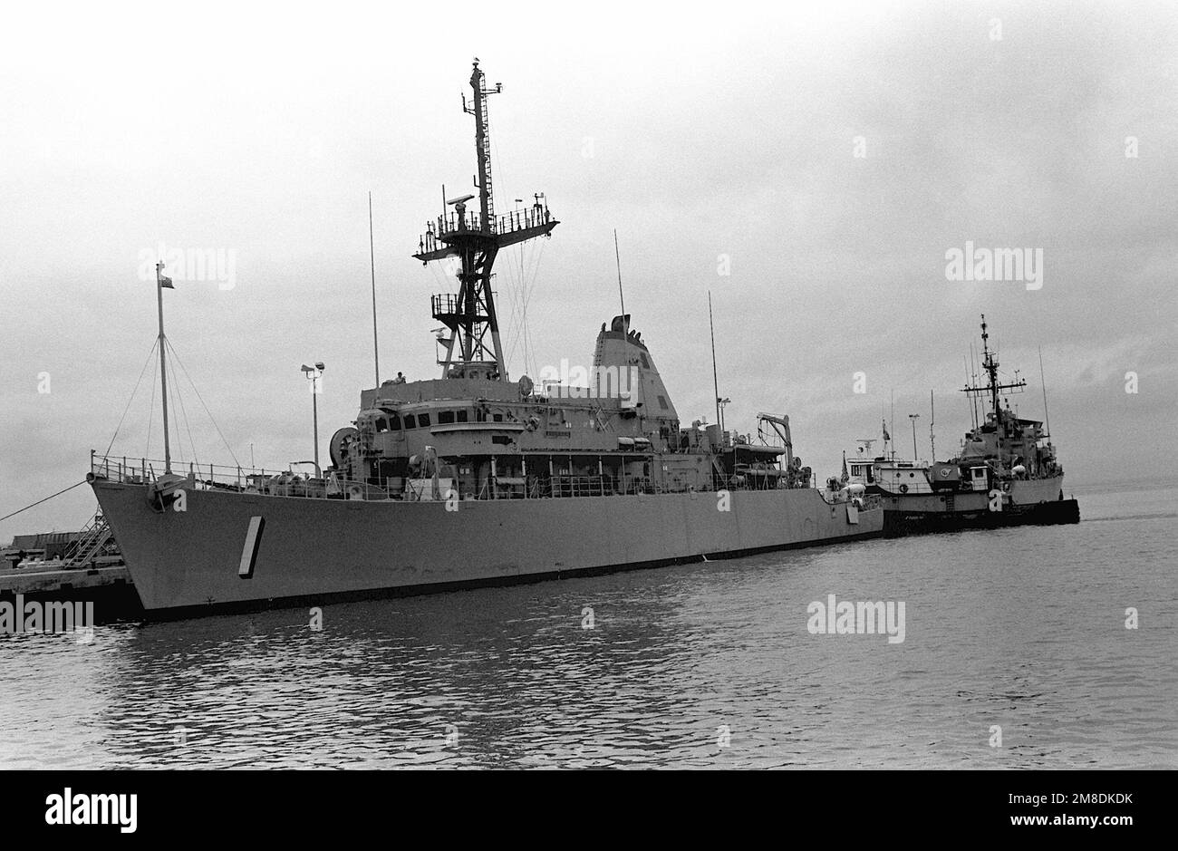The mine countermeasure ship USS AVENGER (MCM-1) is docked at a pier ...