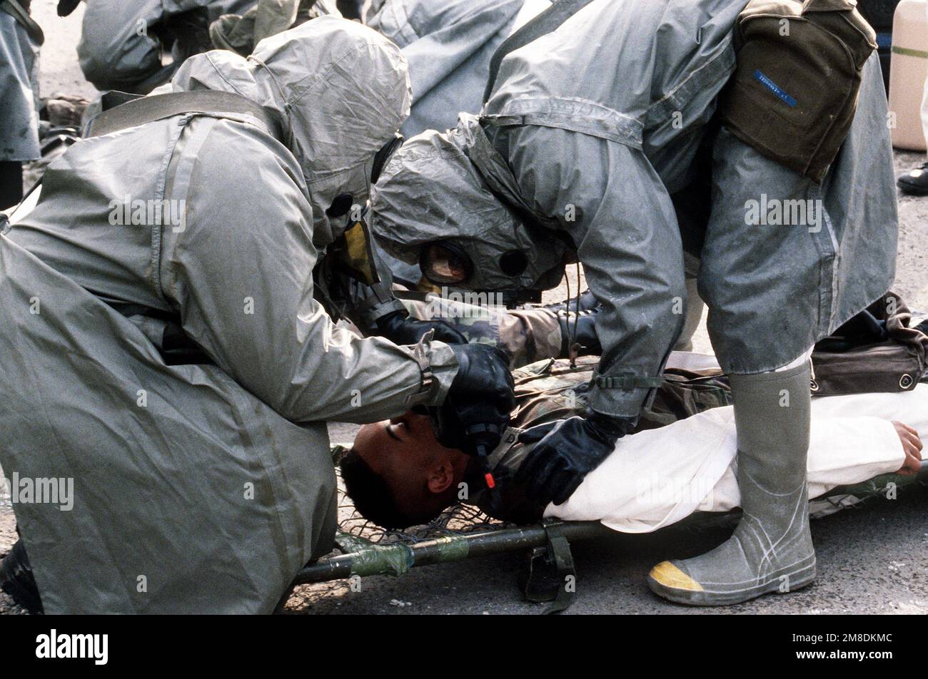 Medical personnel wearing nuclear-biological-chemical (NBC) protective suits and masks treat a ...