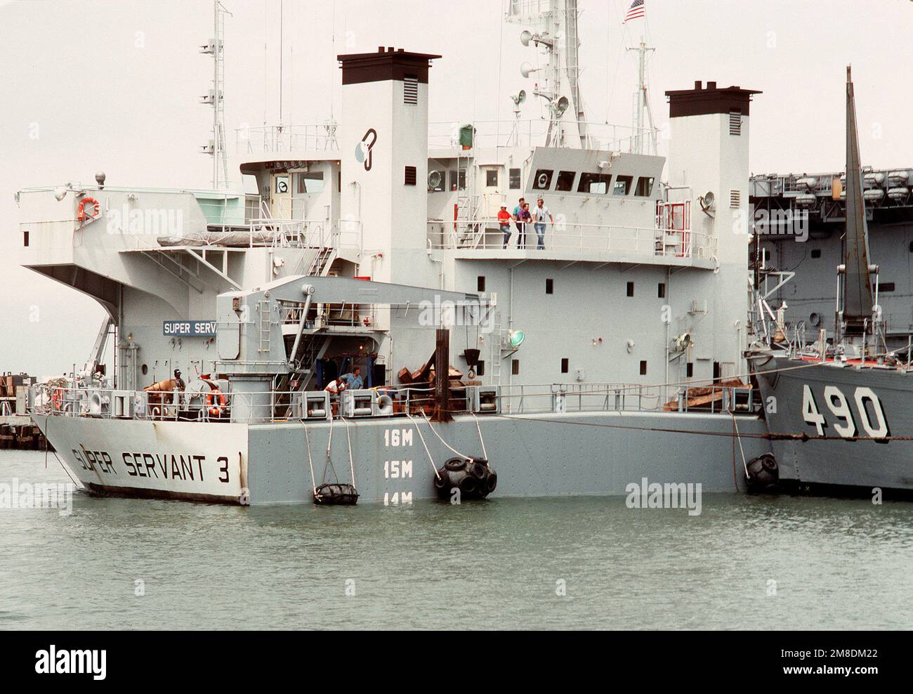 Crew members stand at the railing of the heavy lift ship SUPER SERVANT ...