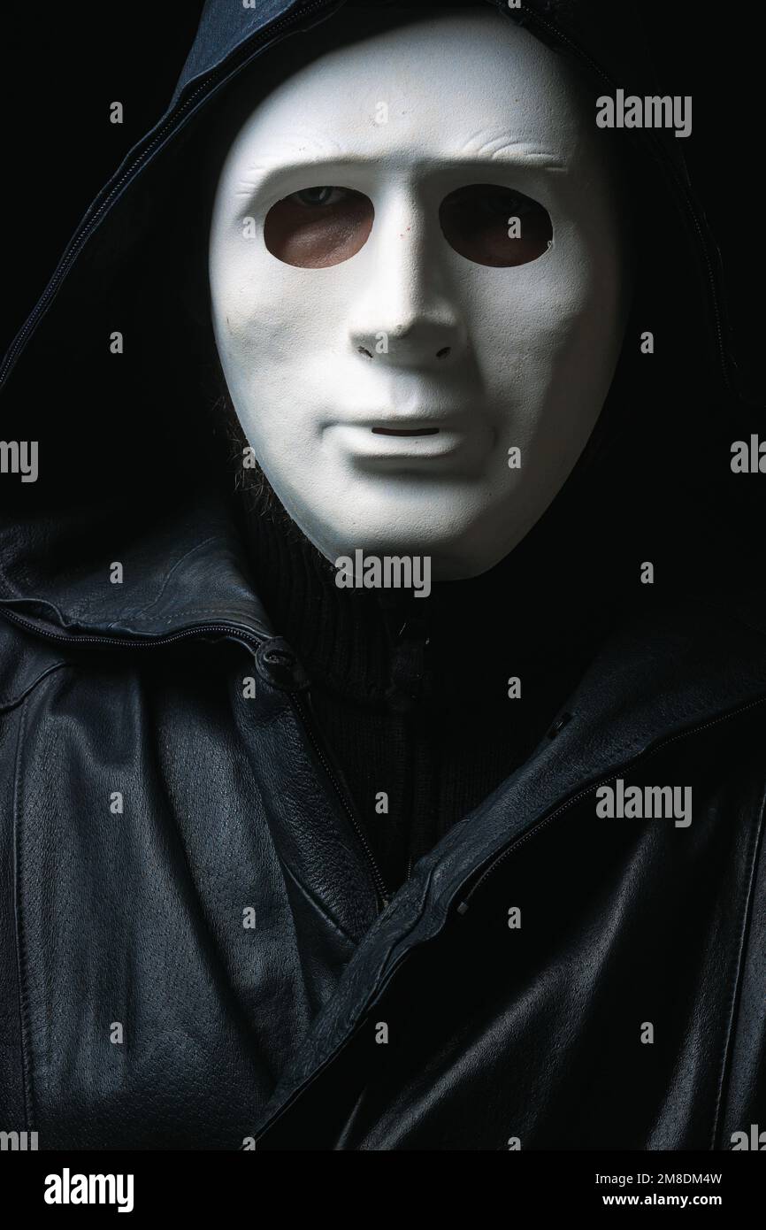 Man in terrible face mask staring at camera against dark background ...