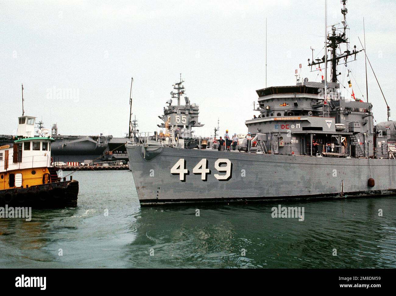 A harbor tug tows the ocean minesweeper USS IMPERVIOUS (MSO-449) toward ...