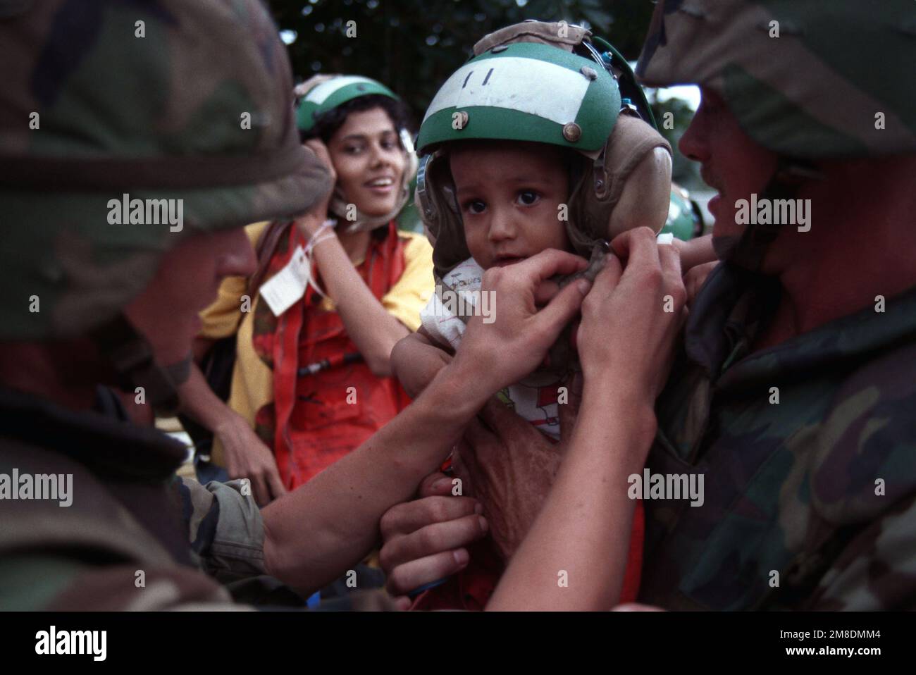 A Marine buckles the chin strap on a child's cranial helmet before a ...