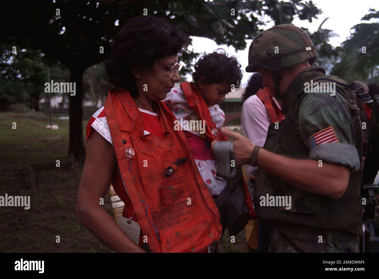 A Marine at the U.S. Embassy places a life preserver on a child before ...