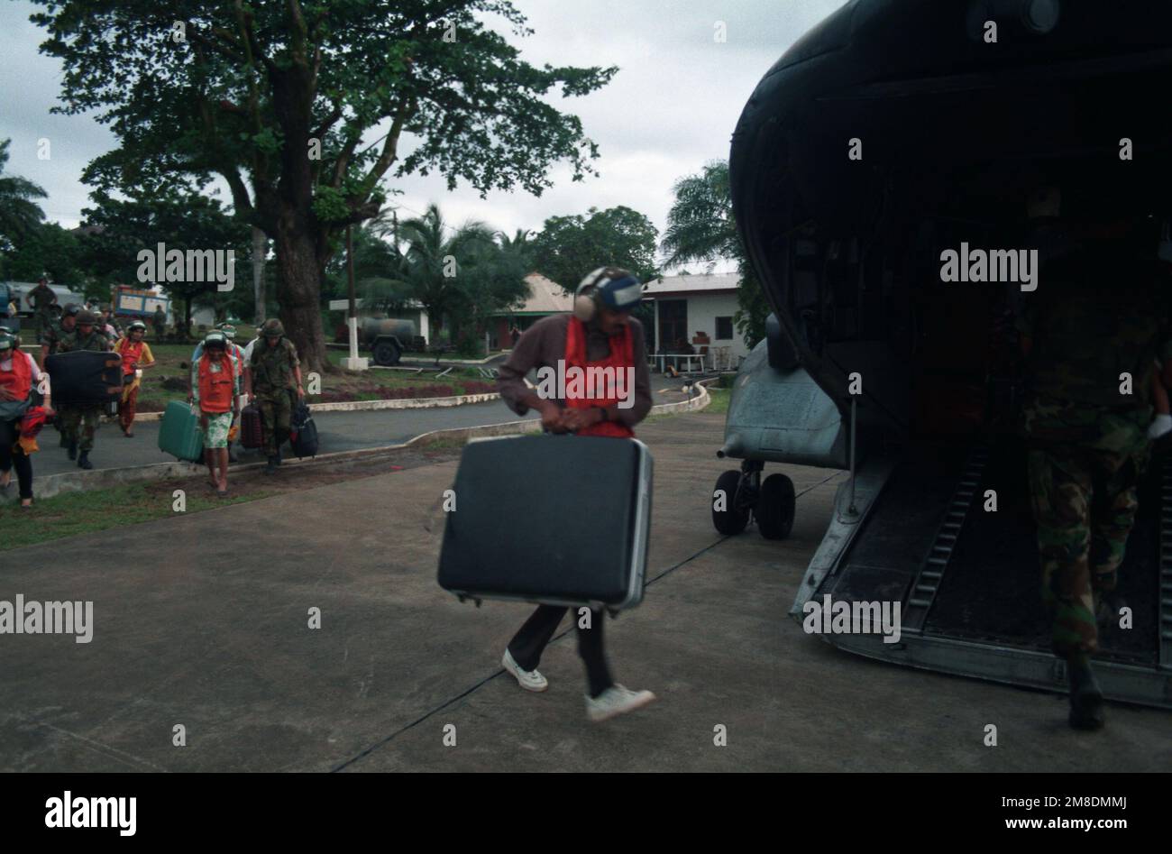 A man fleeing Liberia's civil war carries his suitcase onto a Marine ...