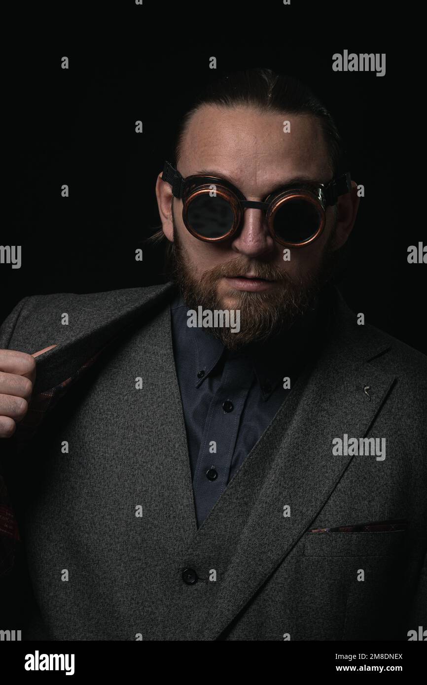 charismatic man in a classic suit and steampunk goggles on a black ...