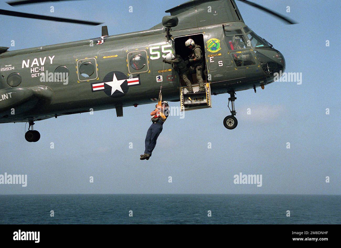 A sailor is transferred to a ship from a UH-46 Sea Knight helicopter of ...