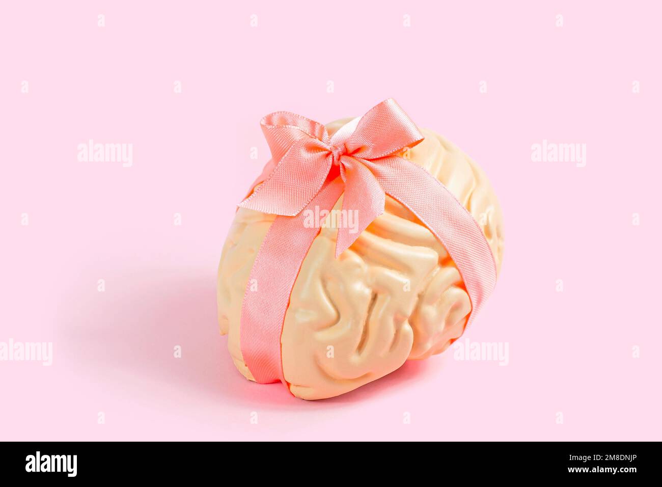 Bright pink human brain model with satin bow on pastel background ...