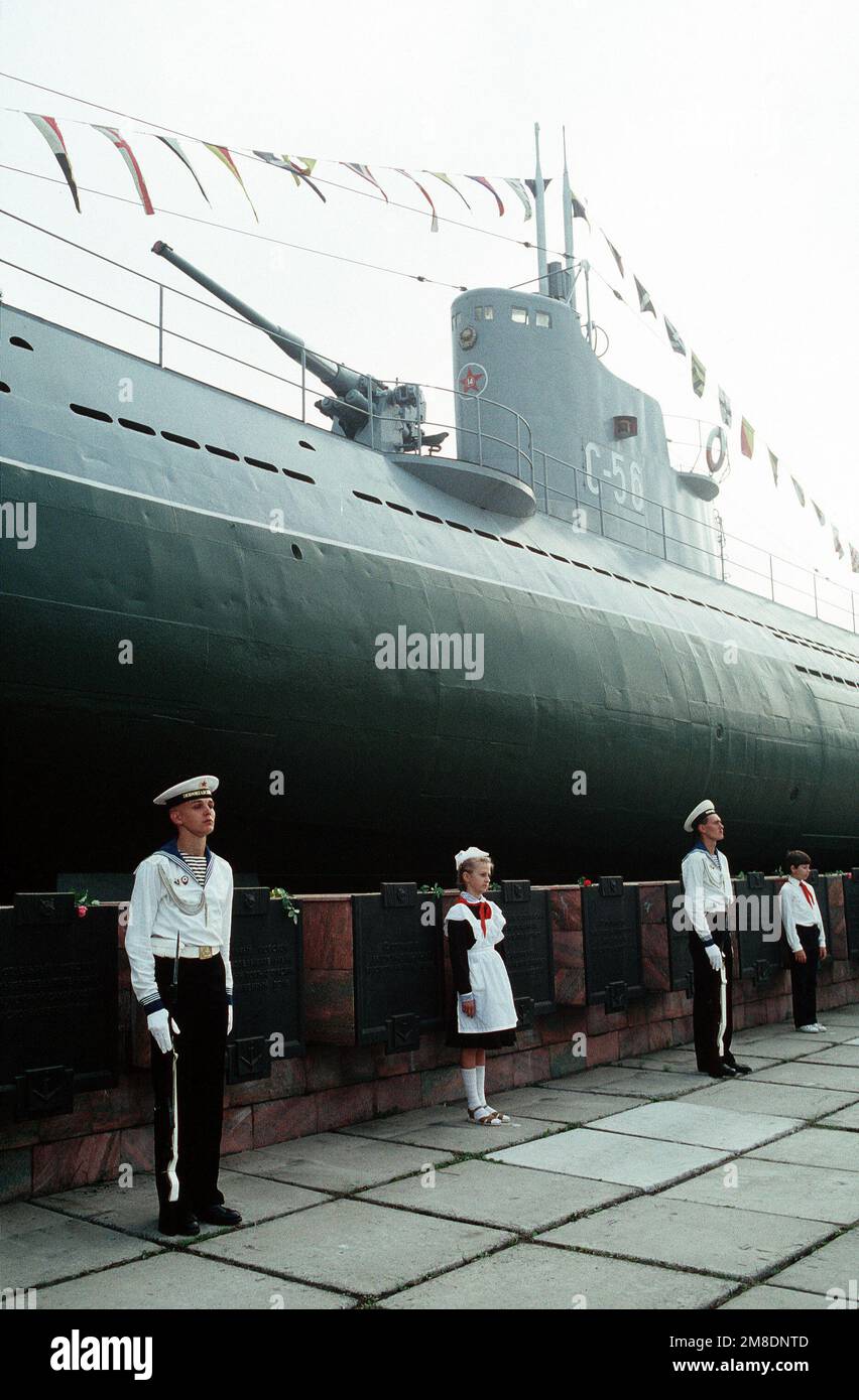 Soviet sailors and schoolchildren stand before a memorial as a wreath ...