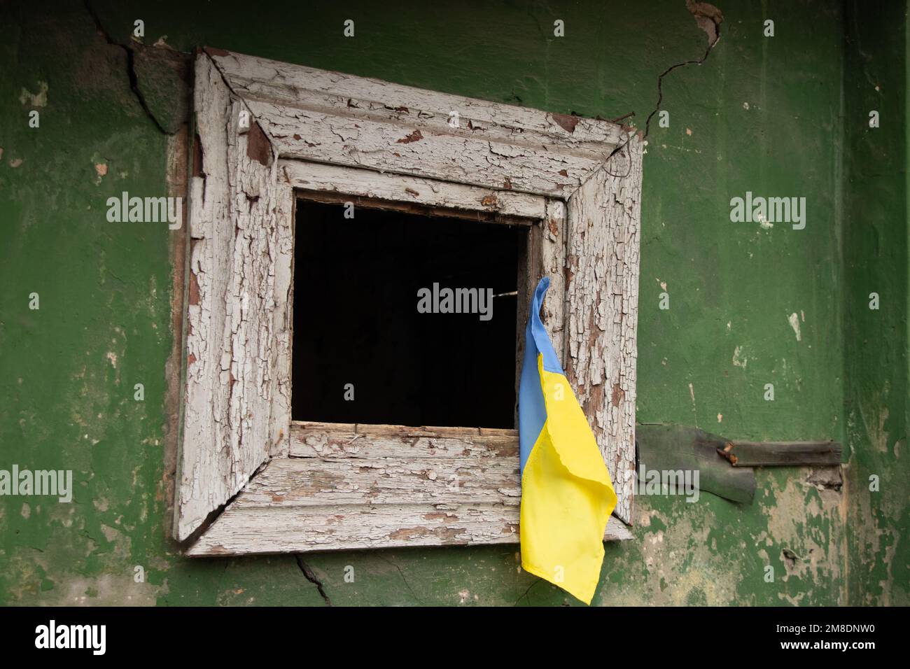 The flag of Ukraine hangs on the window of a destroyed residential ...