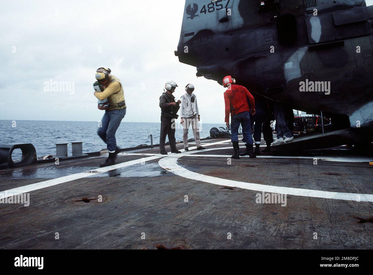 A flight deck crewman carries an infant across the flight deck of the ...