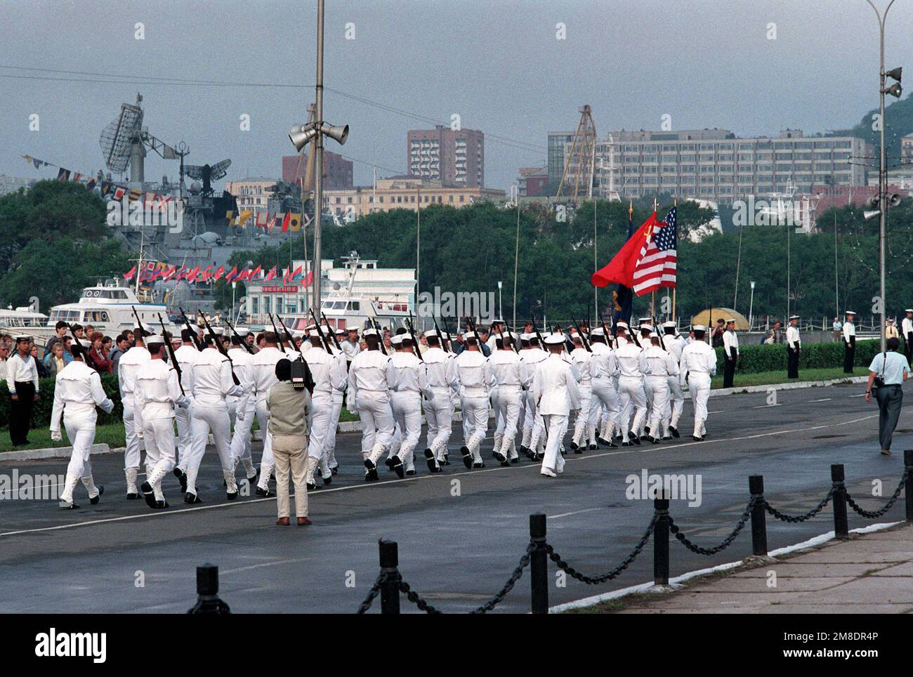 A contingent of American sailors marches along a road following a ...