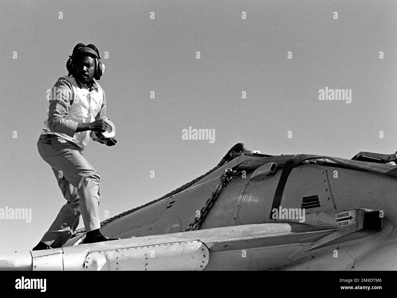 A chief petty officer stands on the wing of a damaged Attack Squadron ...