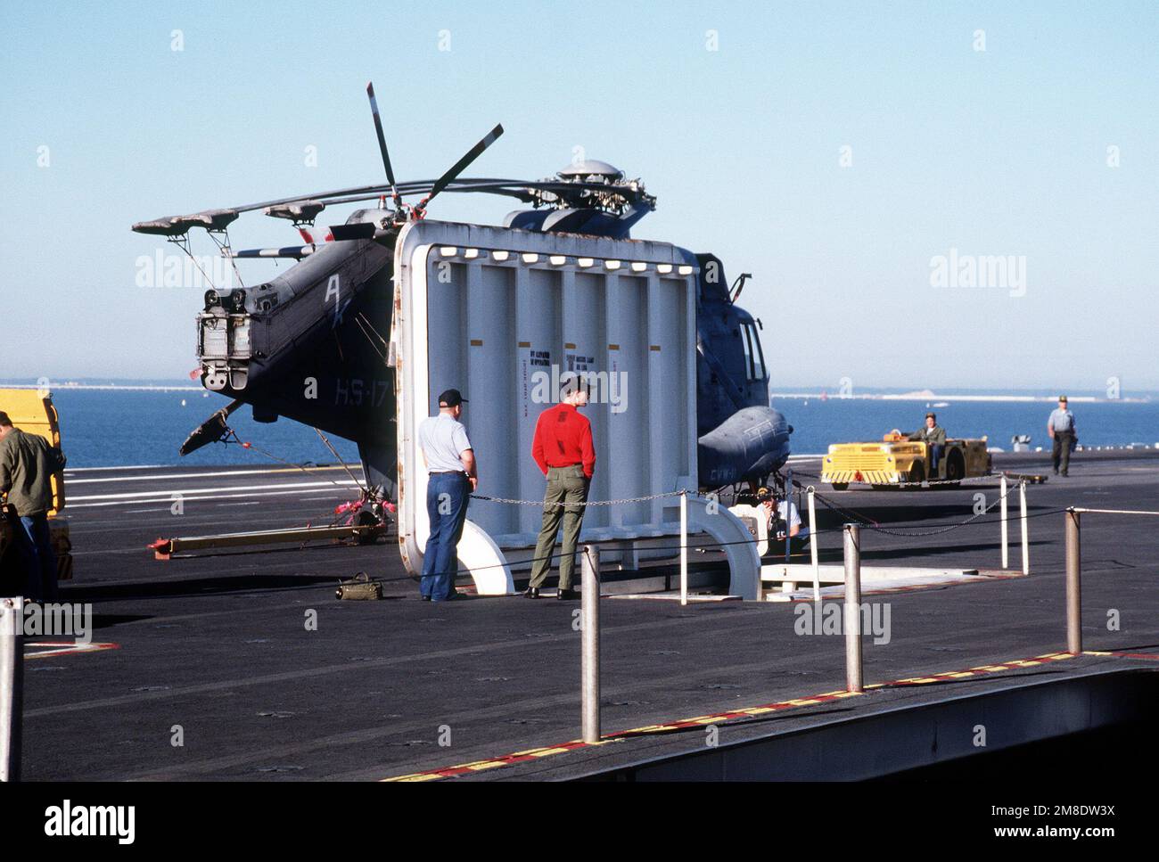 Crew members stand beside an open magazine elevator on the flight deck ...