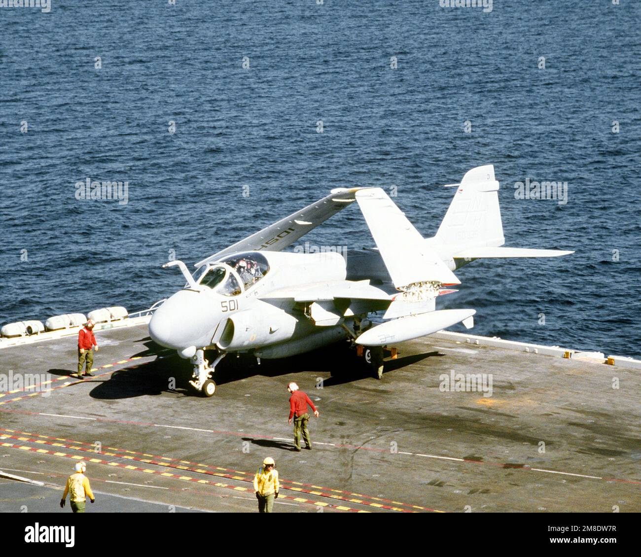Flight deck crew members stand by an Attack Squadron 95 (VA-95) A-6E ...