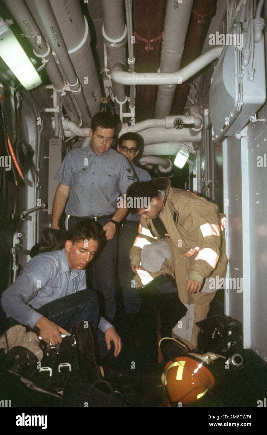 A member of a repair party removes his protective coveralls as another ...