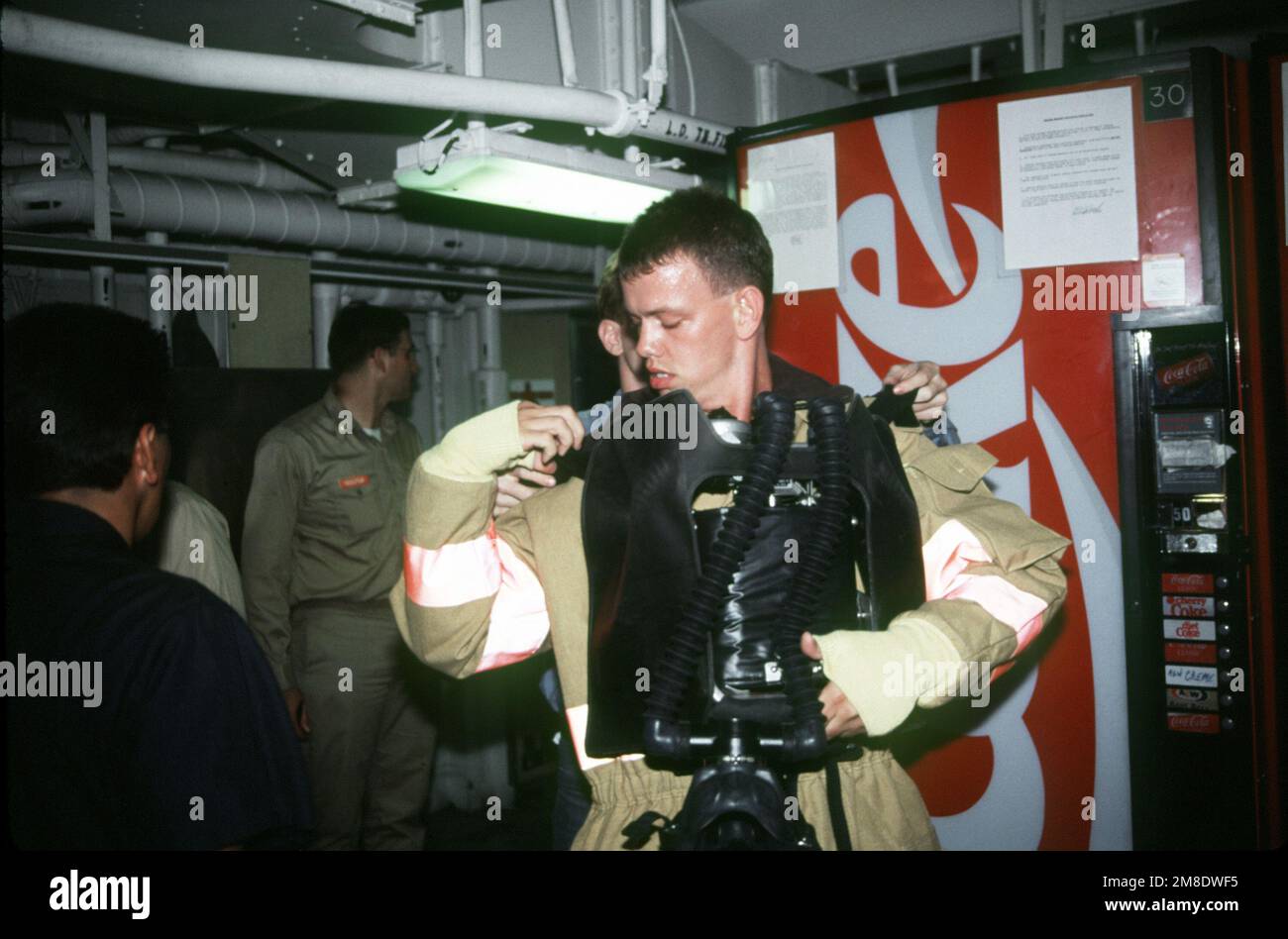 A member of a repair party gets some assistance in donning an oxygen ...
