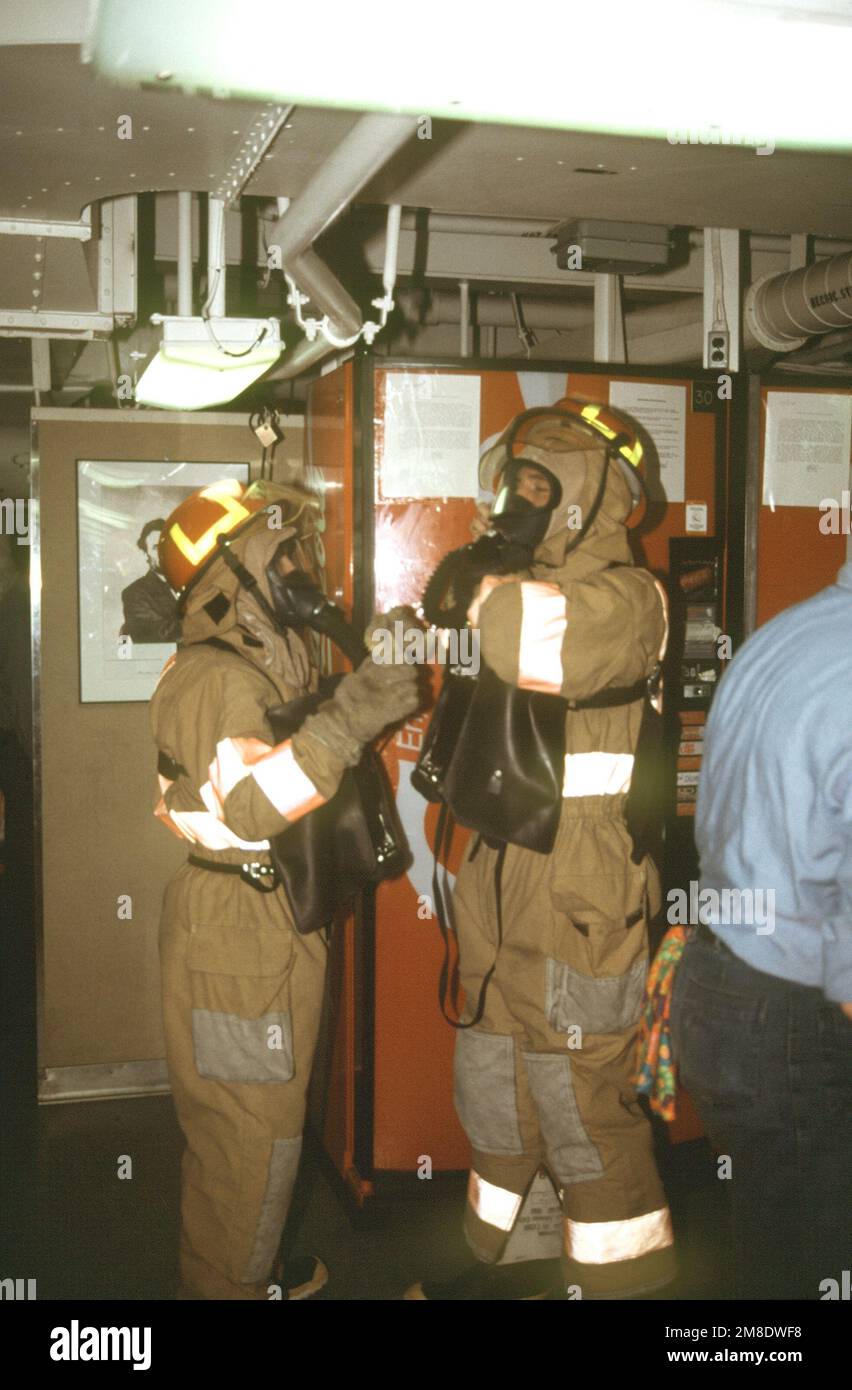 One member of a repair party helps a fellow sailor don an oxygen ...