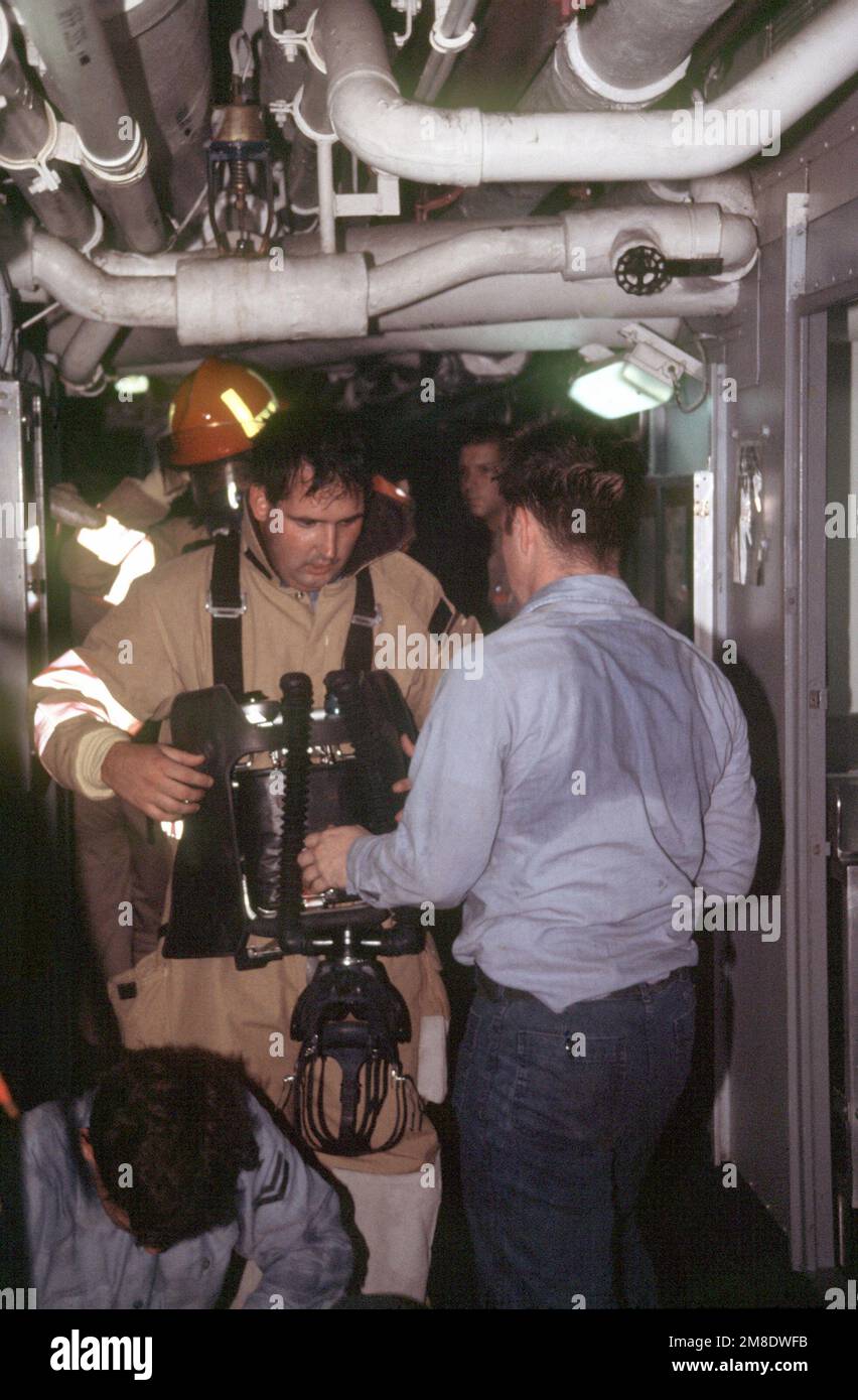 A member of a repair party gets some assistance from a fellow sailor in ...