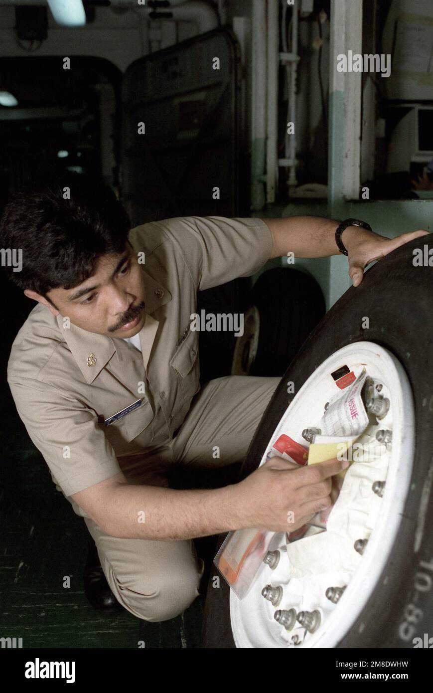 A chief aviation storekeeper checks the paperwork on an aircraft wheel ...