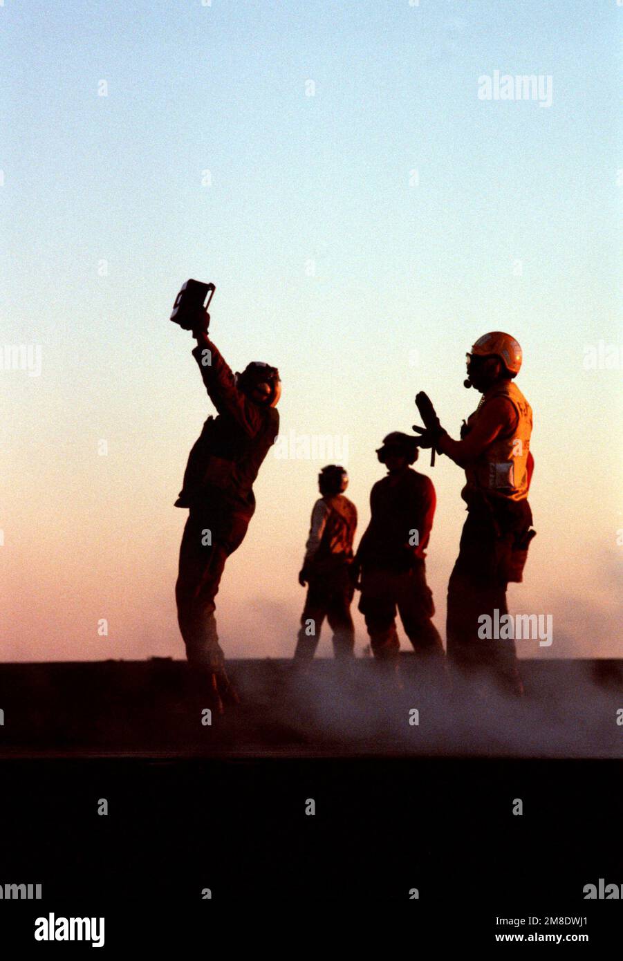 A catapult crewman displays the weight of the next aircraft to be ...