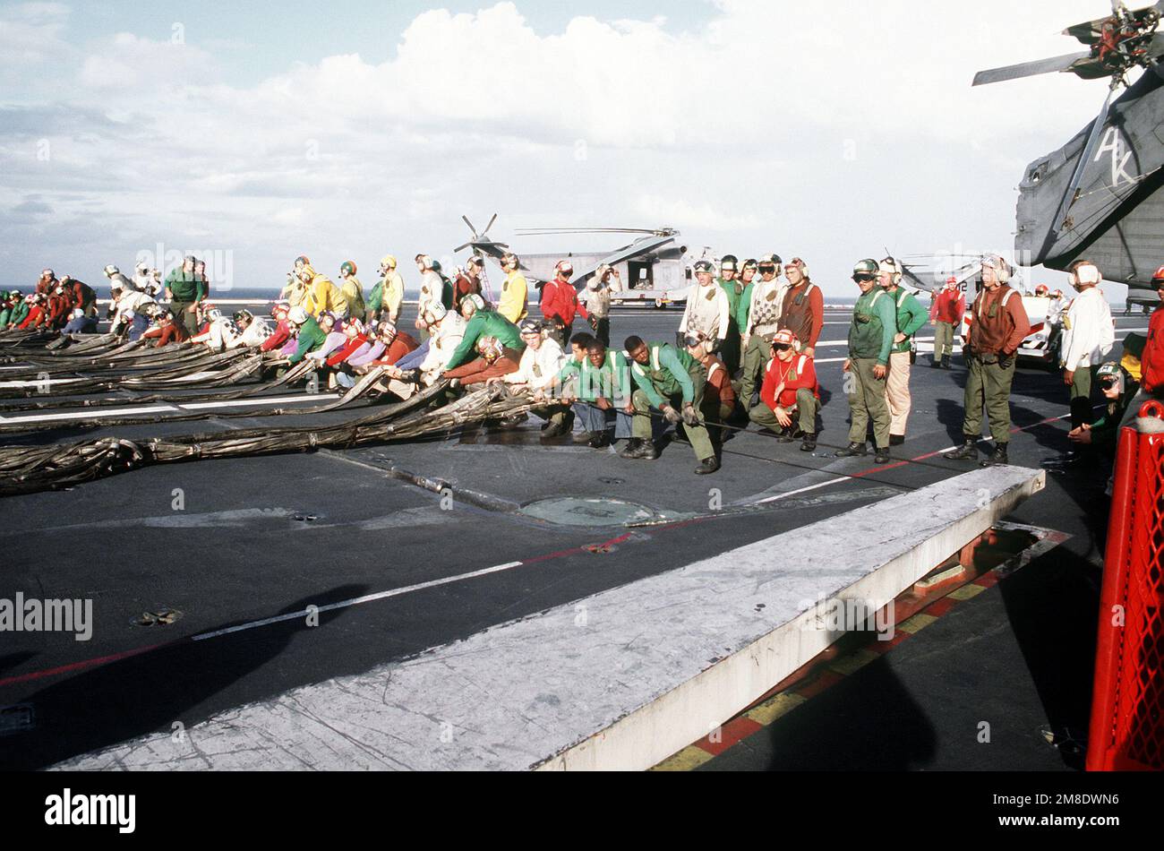 Flight deck crew members spread out the crash barricade during a drill ...