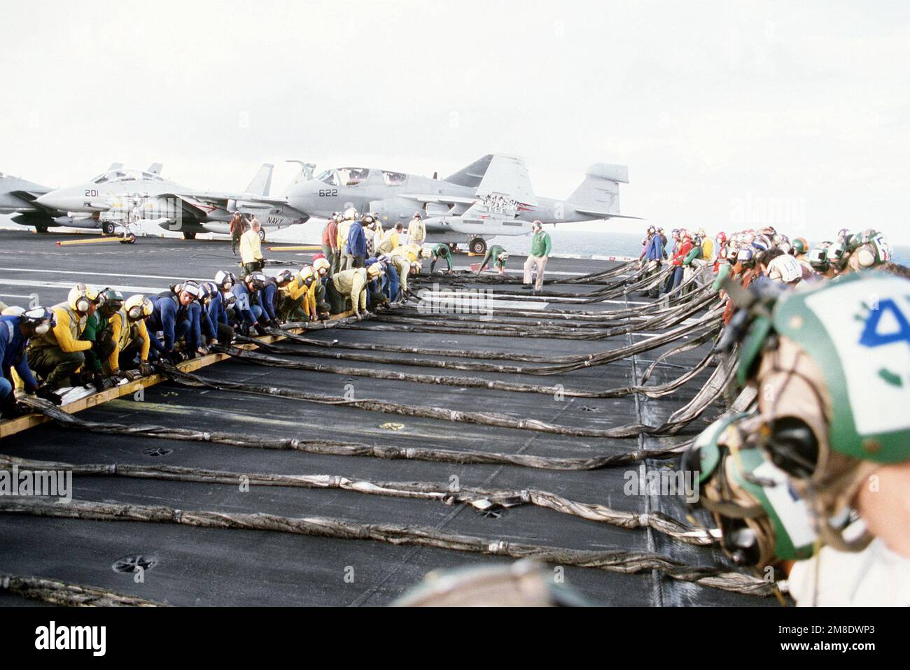 Flight deck crew members spread out the crash barricade during a drill ...