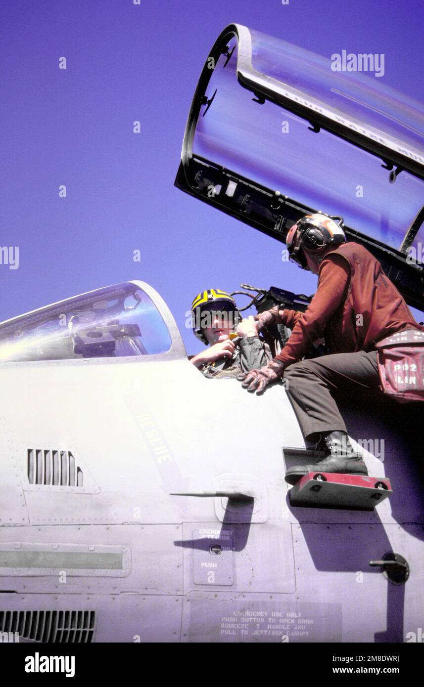An air crew member assists CAPT. William B. Hayden, commanding officer ...