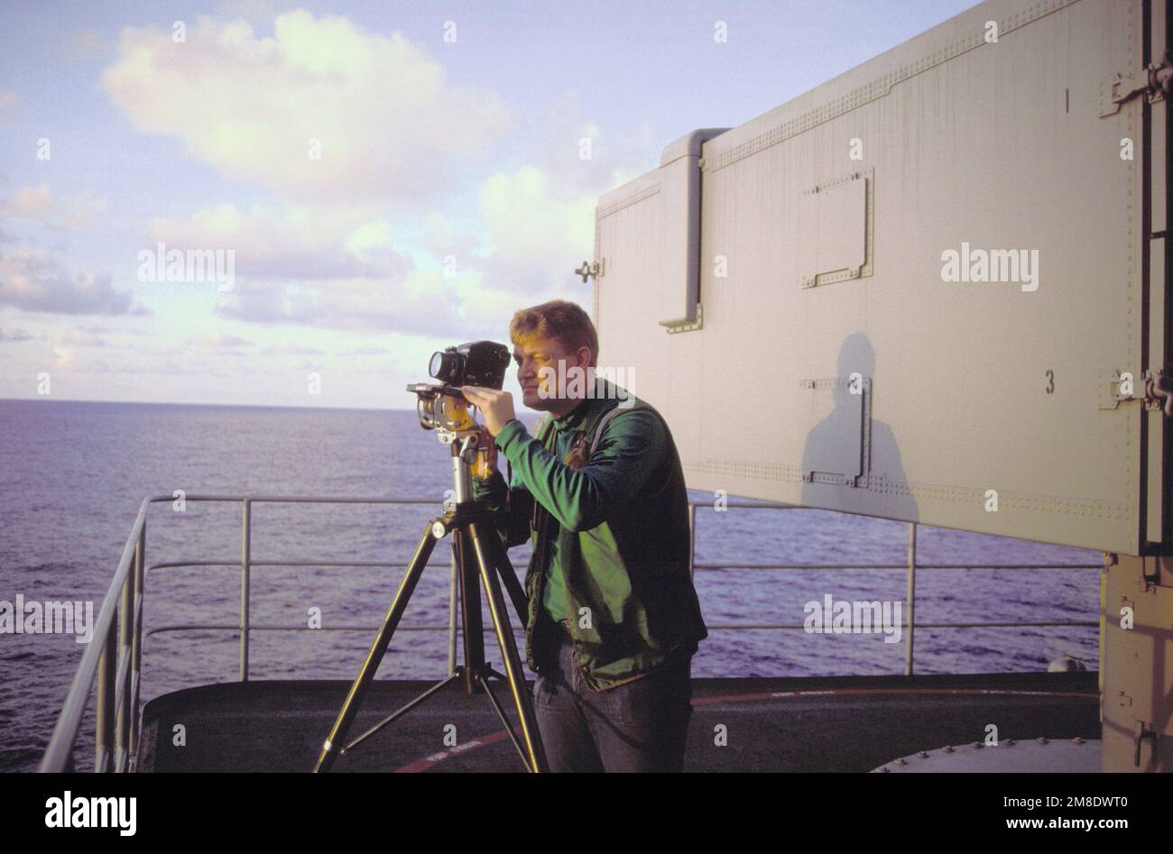 Photographer's Mate 2nd Class Dennis Taylor sets up his camera as he ...