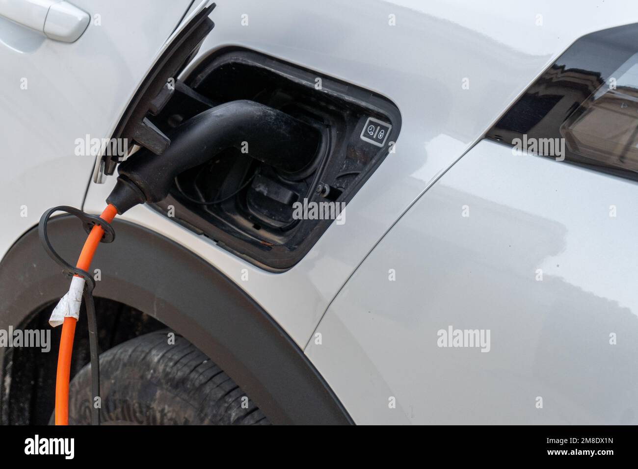 A closeup of white car being charged at electric vehicle charging ...