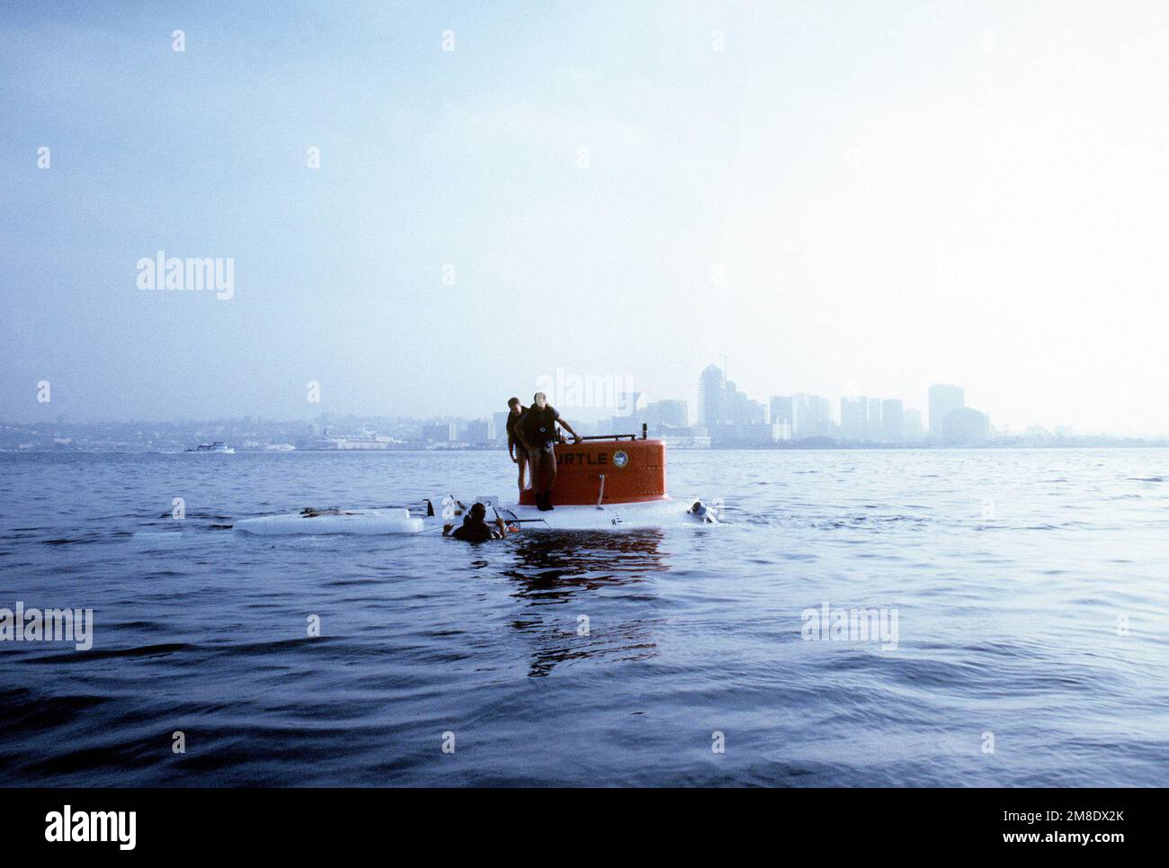 Two crew members stand on the hull of the U.S. Navy deep submergence ...