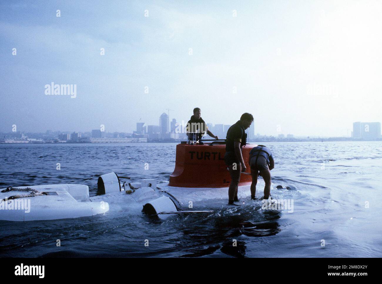 Crew members stand on the hull of the U.S. Navy deep submergence ...