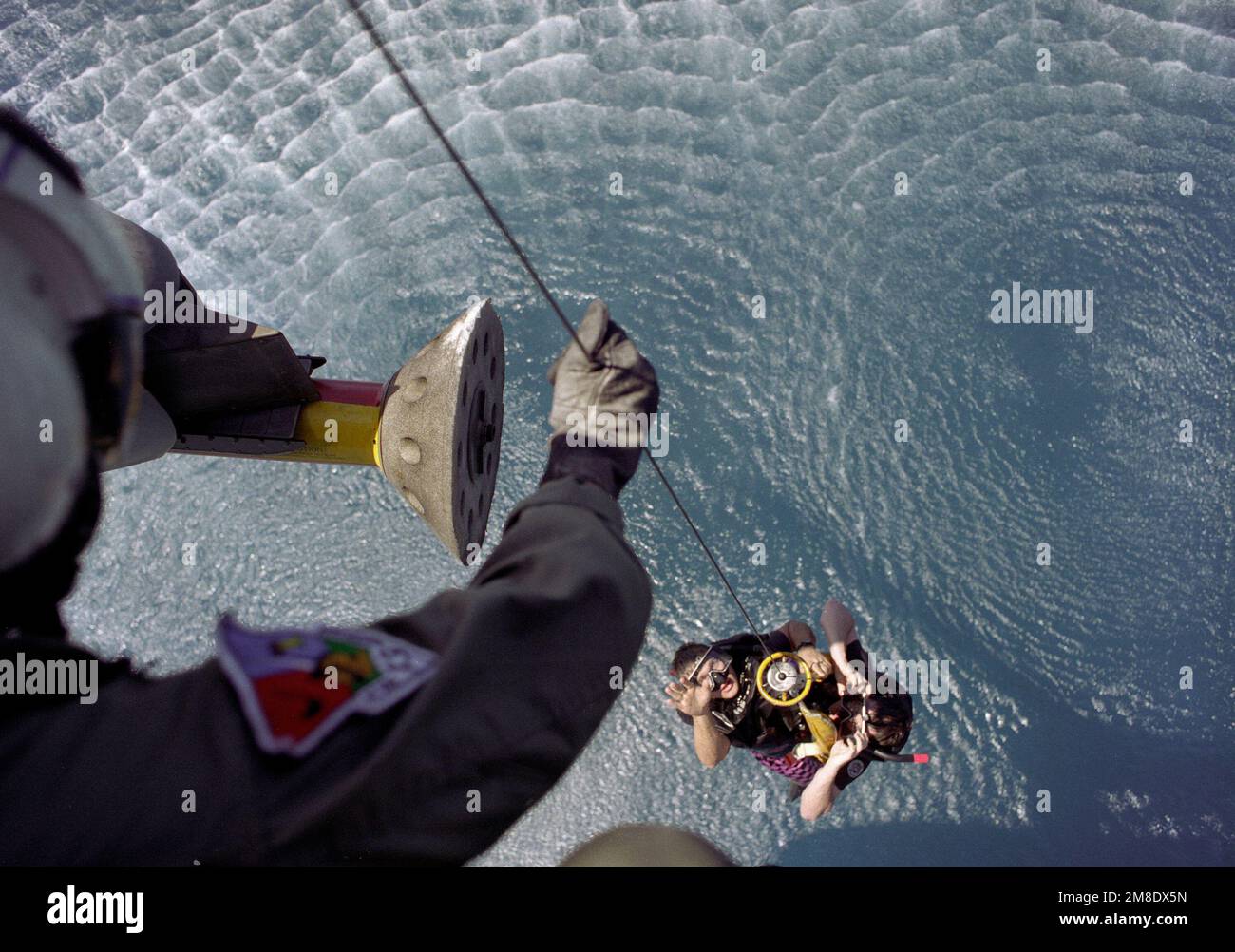 Rescue swimmers are hoisted aboard an SH-3H Sea King helicopter for ...