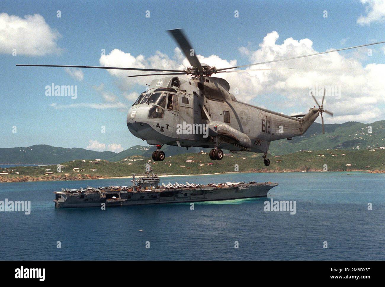 An SH-3H Sea Kikng helicopter hovers near the nuclear-powered aircraft ...