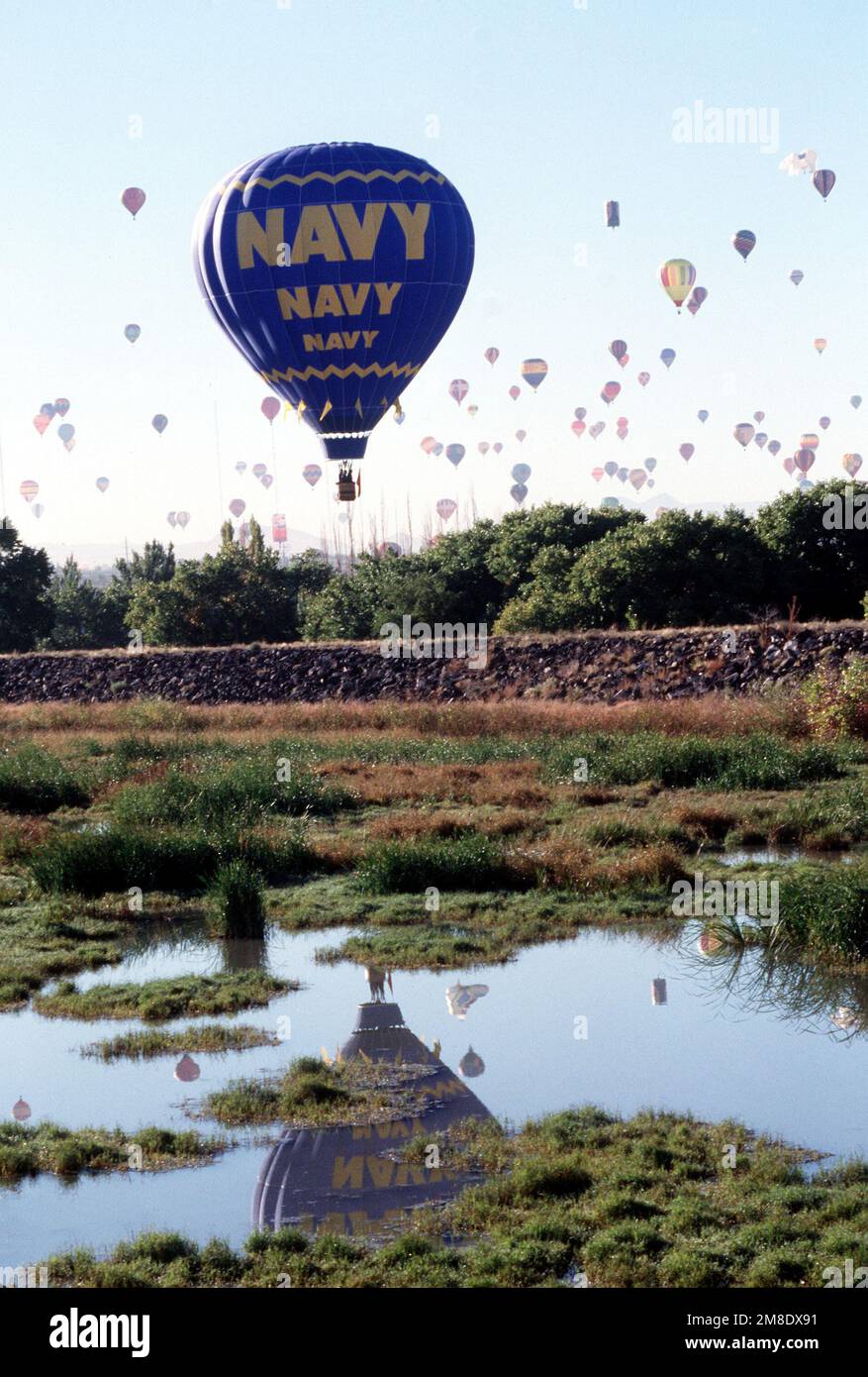 A U.S. Navy hot air balloon and dozens of other balloons float over the ...